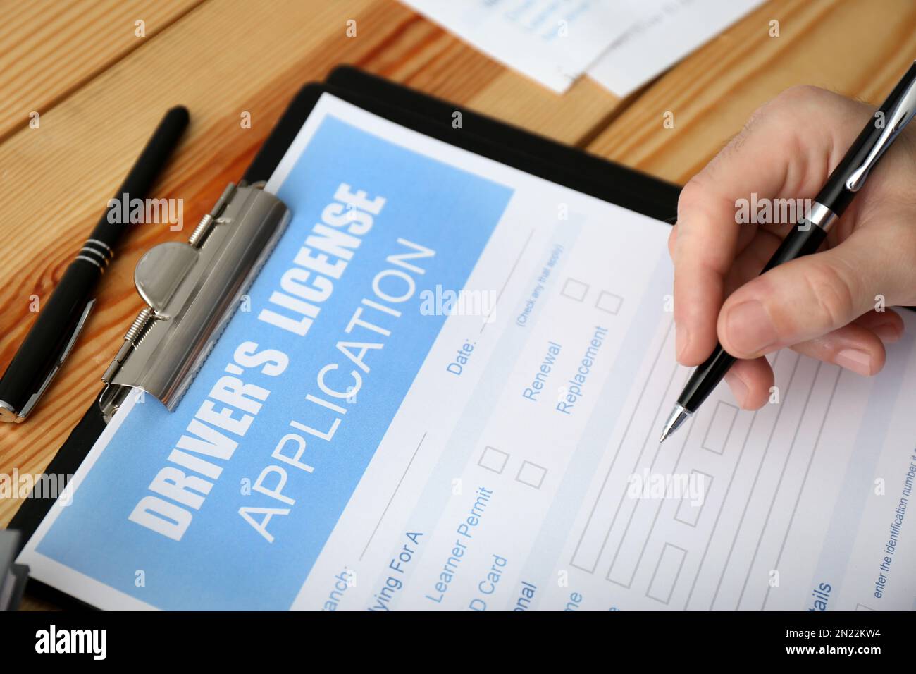 Man filling in driver's license application form at wooden table, closeup Stock Photo - Alamy