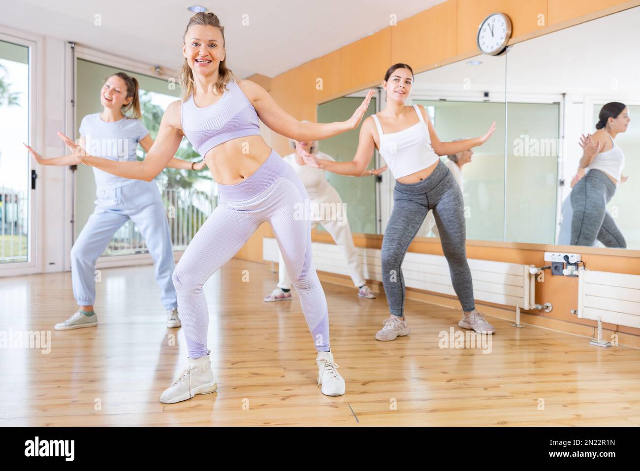 Active middle-aged woman practicing aerobic dance in training hall ...