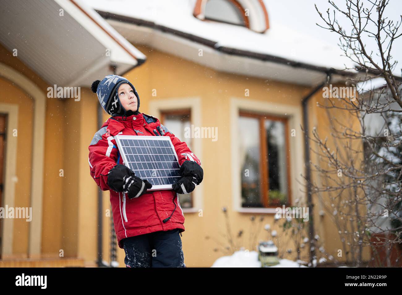 Boy with solar panel against house in winter. Alternative energy ...