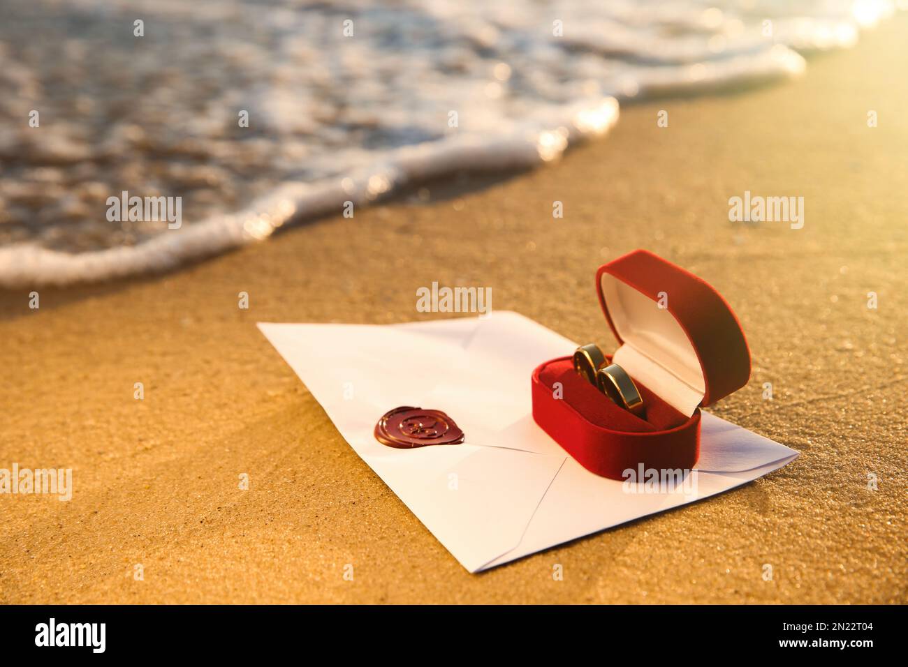 Red box with gold wedding rings and envelope on sandy beach Stock Photo ...