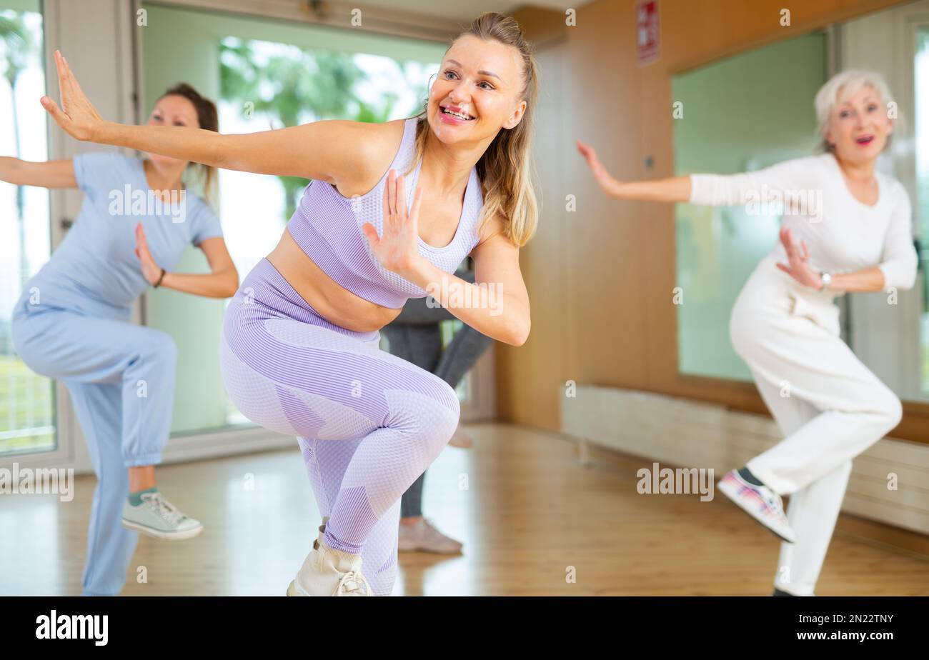 Positive people practicing vigorous lindy hop movements in dance class ...