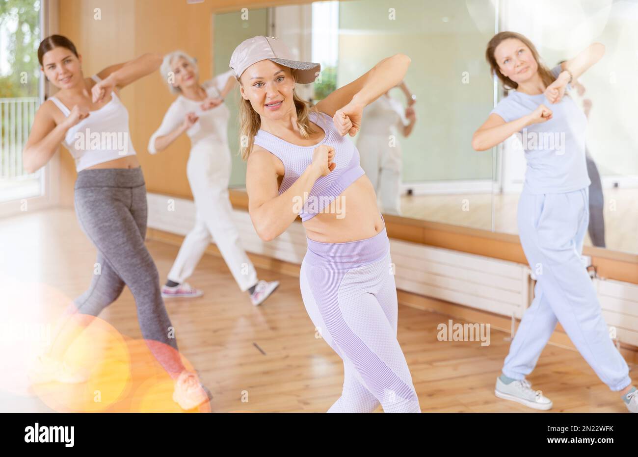 Four active women of different ages performing energetic moves of hands ...
