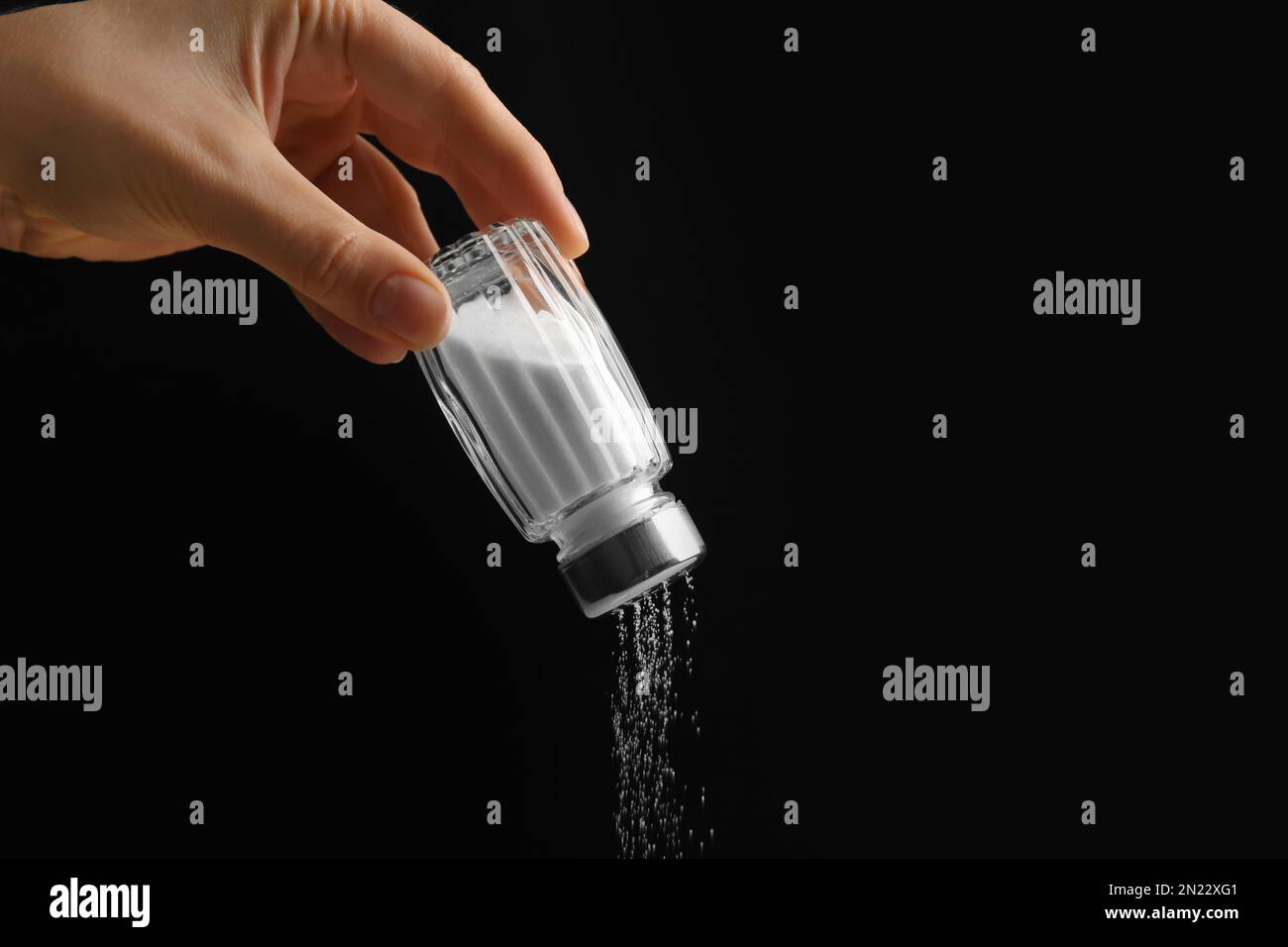 Woman pouring salt from shaker on black background, closeup Stock Photo ...