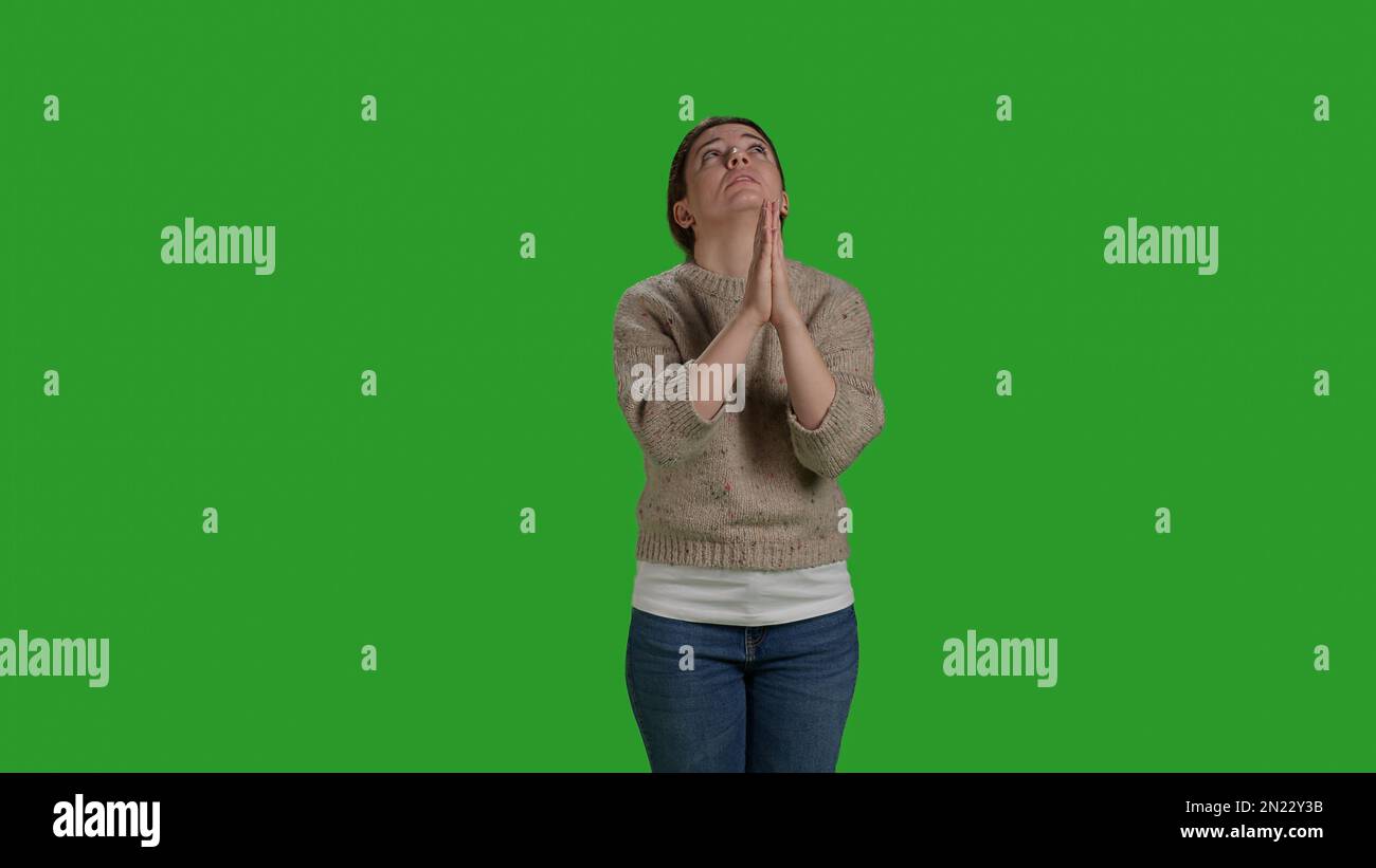 Front view of female model praying to god on camera, holding prayer ...