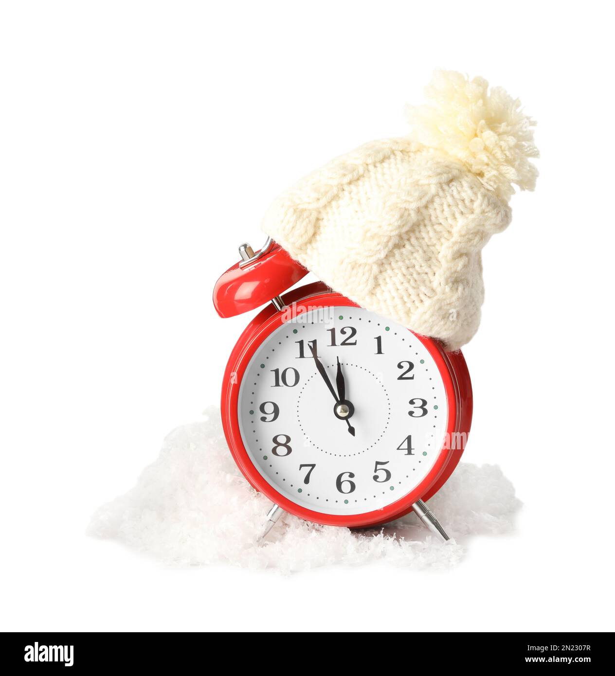 Alarm clock with hat in pile of snow on white background. New Year ...
