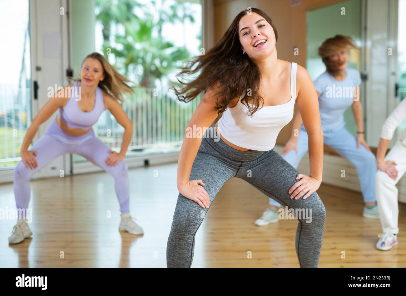 Excited sportive women of different ages dancing with legs wide apart ...
