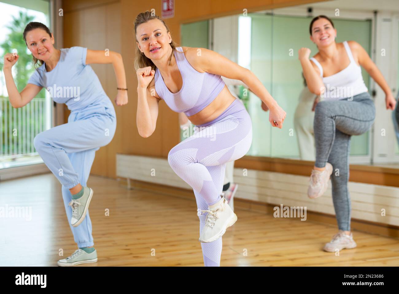 Group of energetic young mature female dancers dancing with knee lift ...