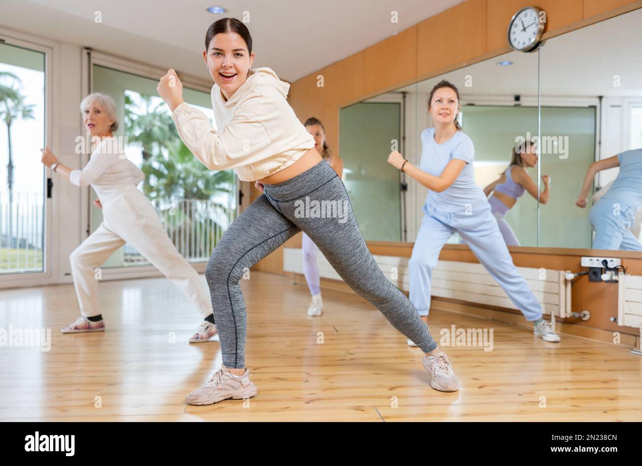 Cheerful energetic female dancers of different ages learning new ...