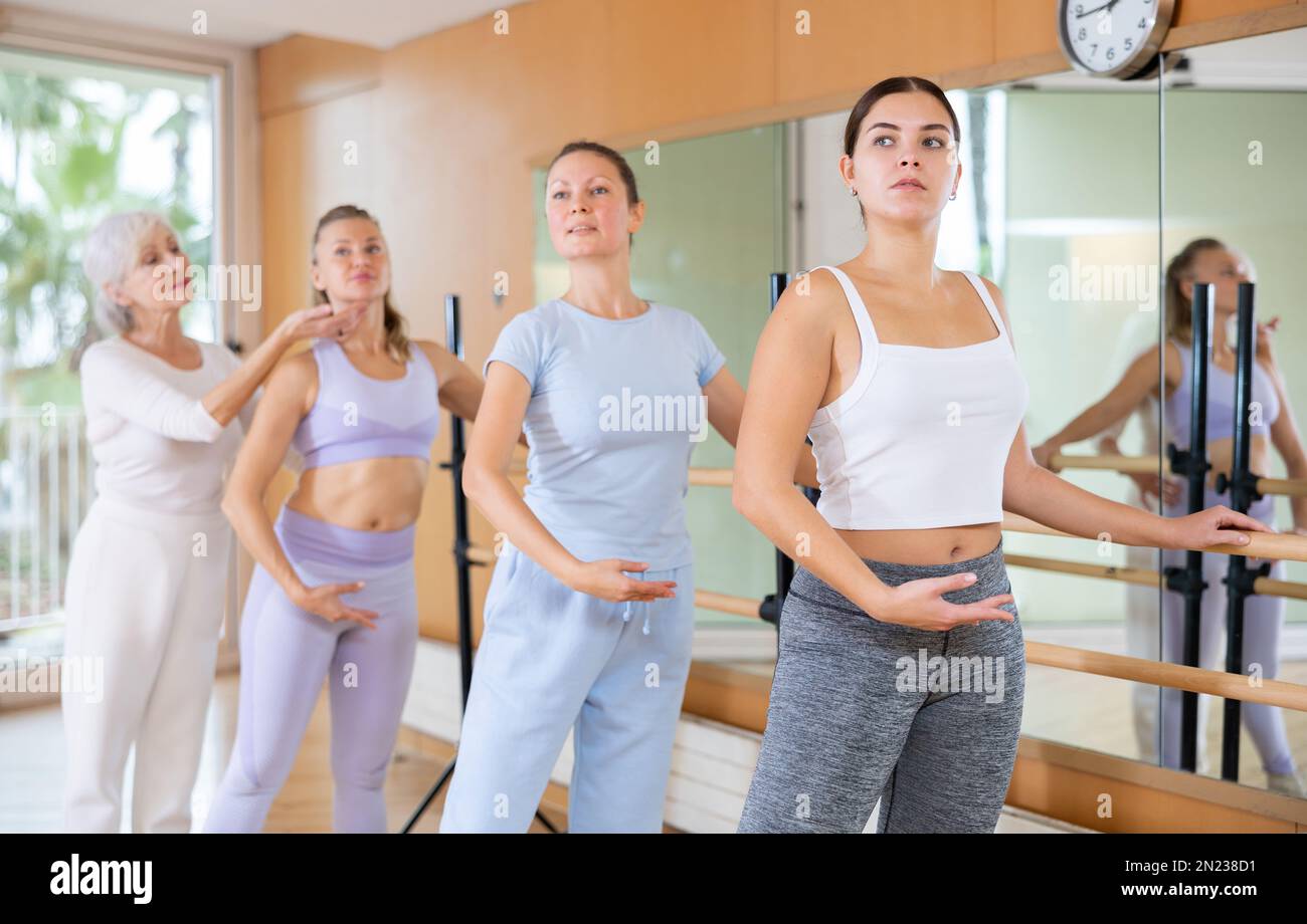 Female ballet instructor adjusting students form in dancing school ...