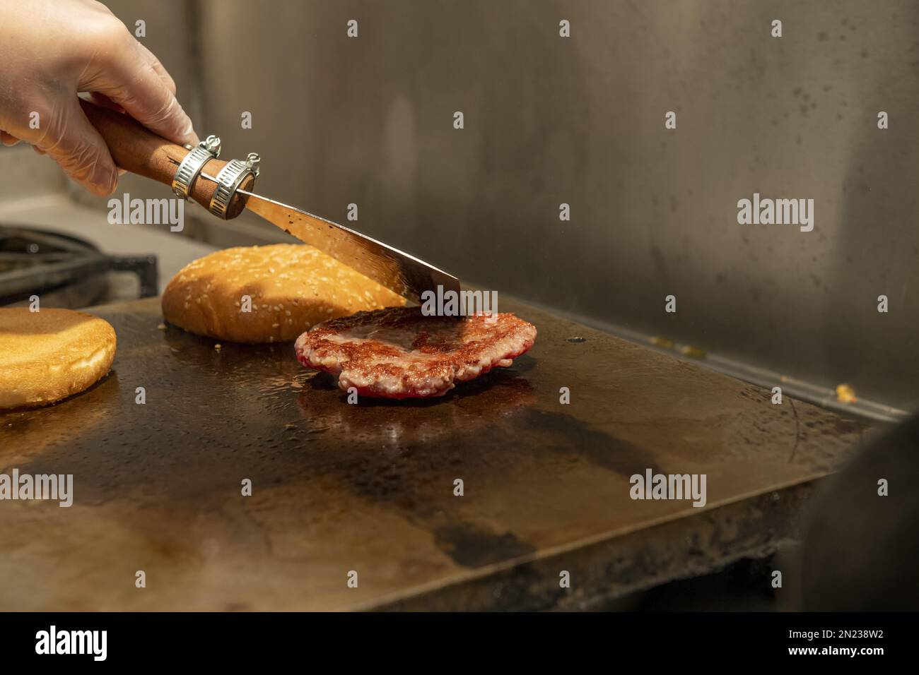 Hands of a chef flipping beef burgers on a restaurant griddle Stock ...