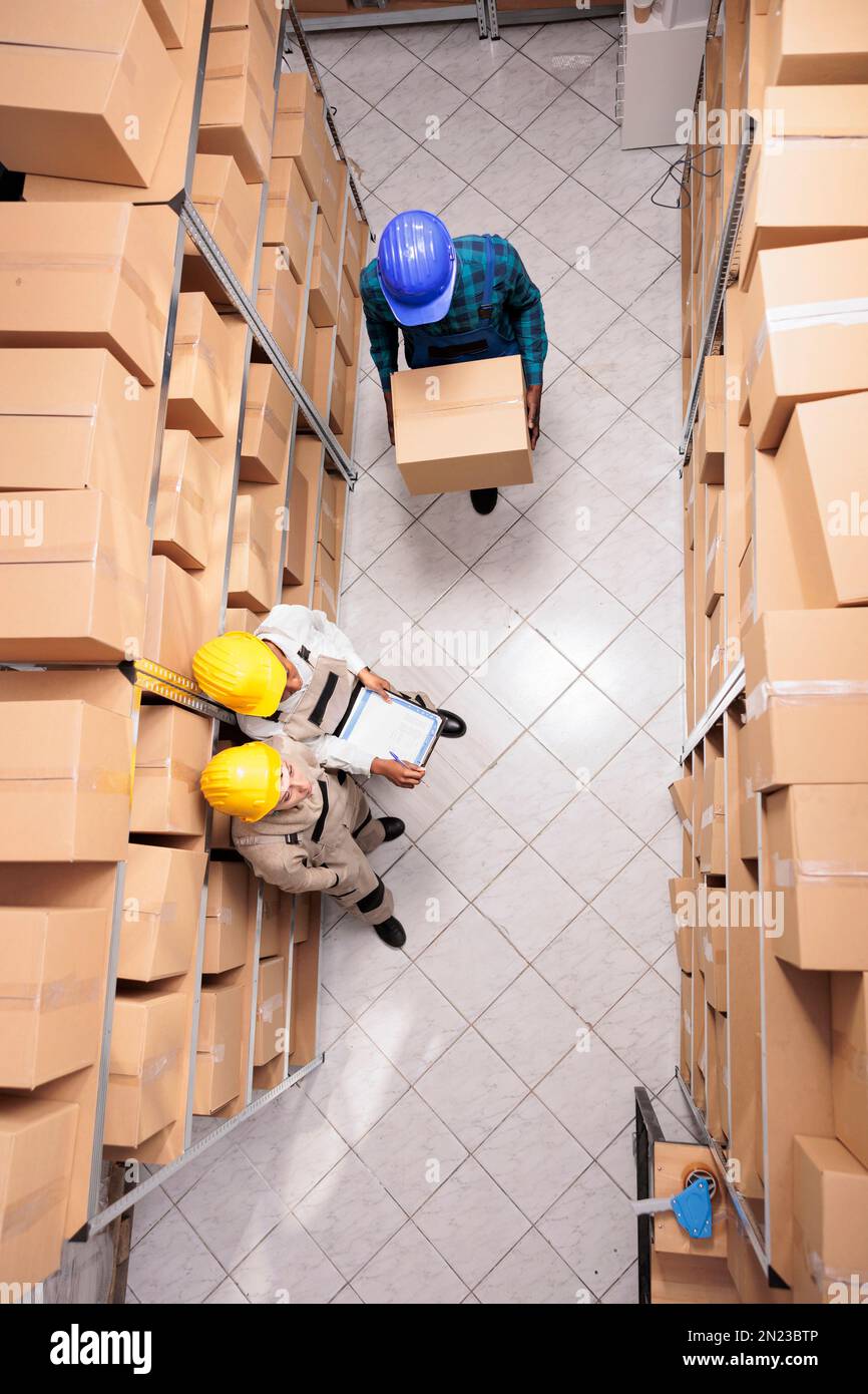 Warehouse employees managing parcels receiving, carrying cardboard box ...