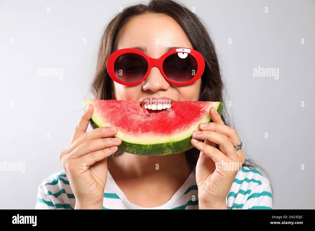 Beautiful young woman eating watermelon on grey background Stock Photo ...
