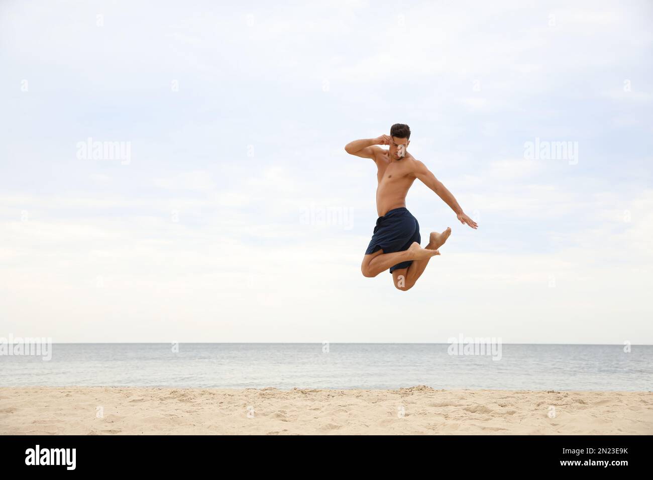 Muscular man jumping on beach, space for text. Body training Stock ...