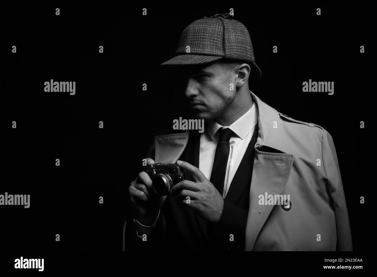 Old fashioned detective with camera on dark background, black and white ...
