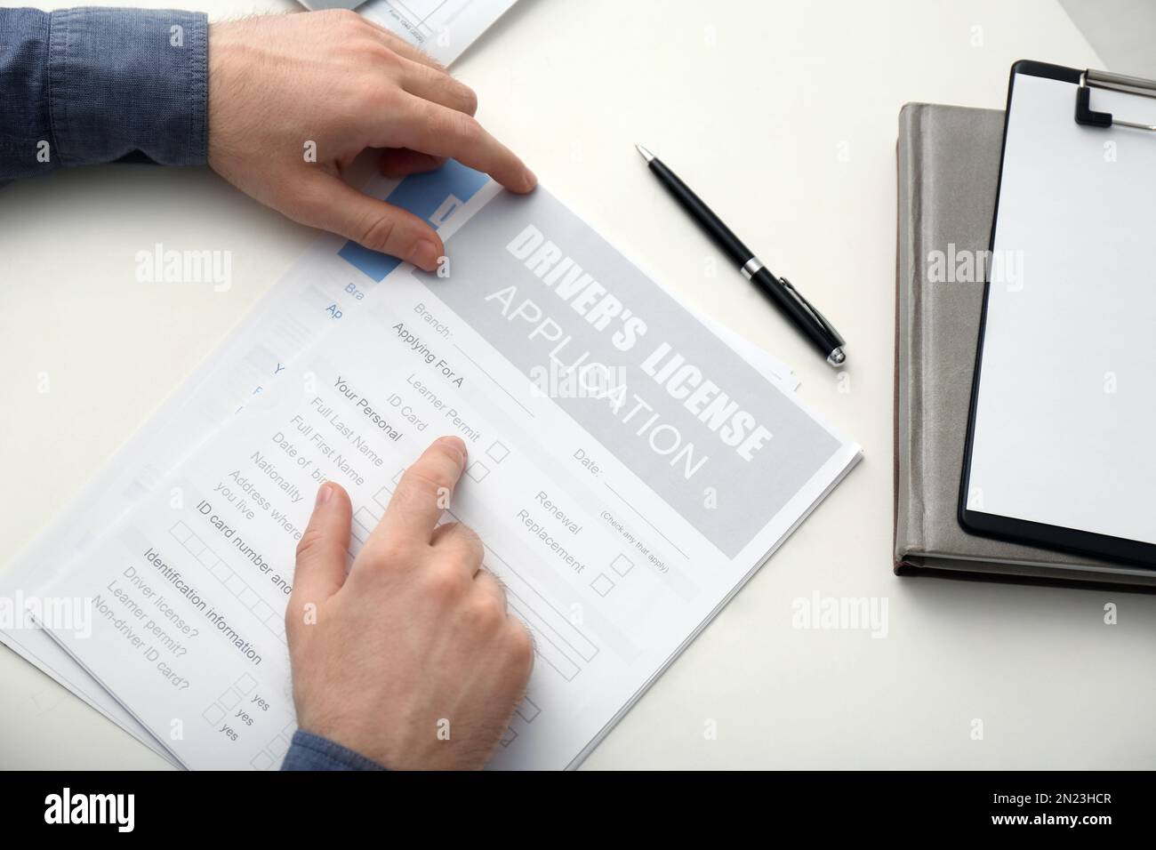 Man with driver's license application form at white table, above view Stock Photo - Alamy