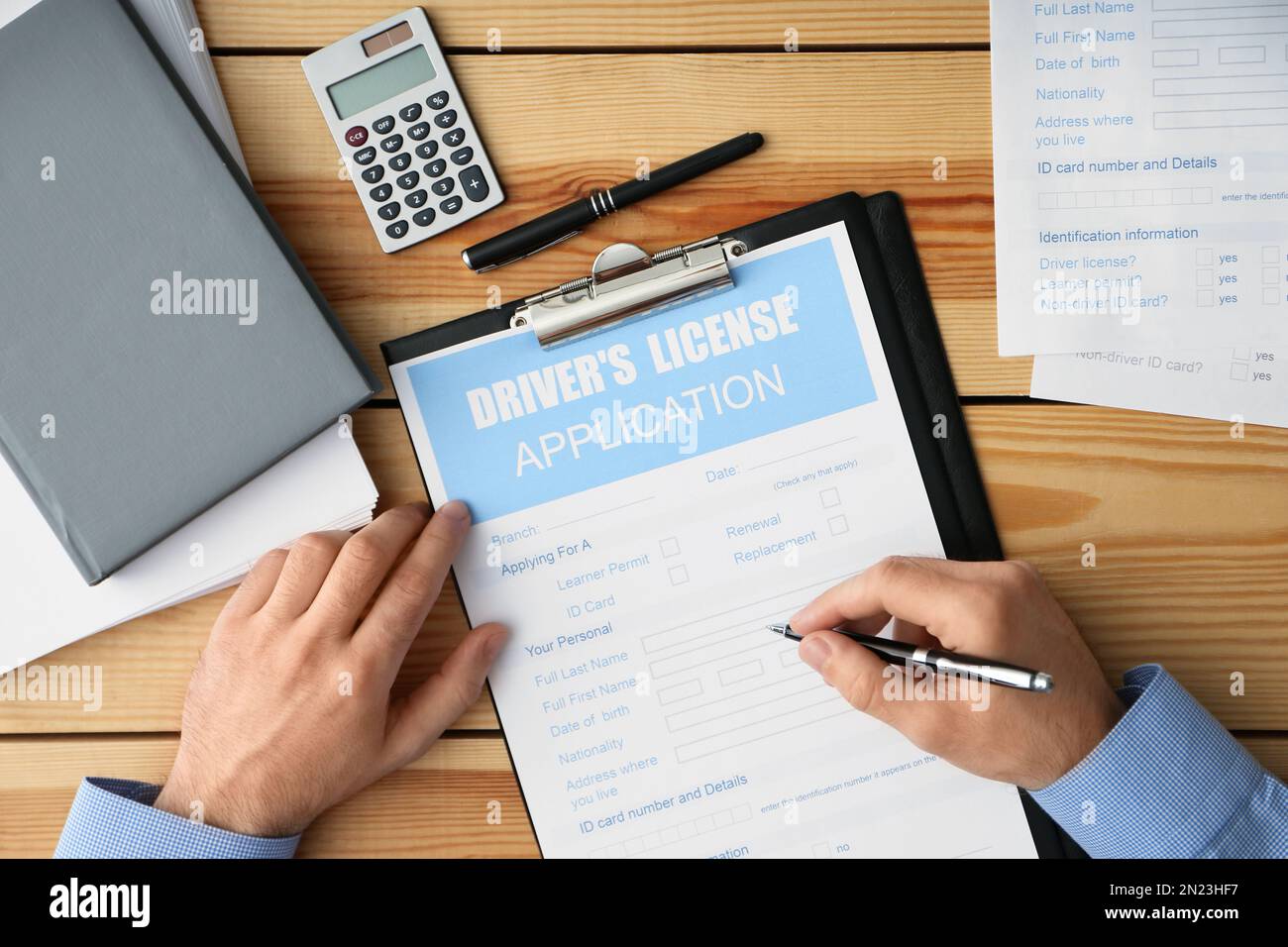 Man filling in driver's license application form at wooden table, top view Stock Photo - Alamy