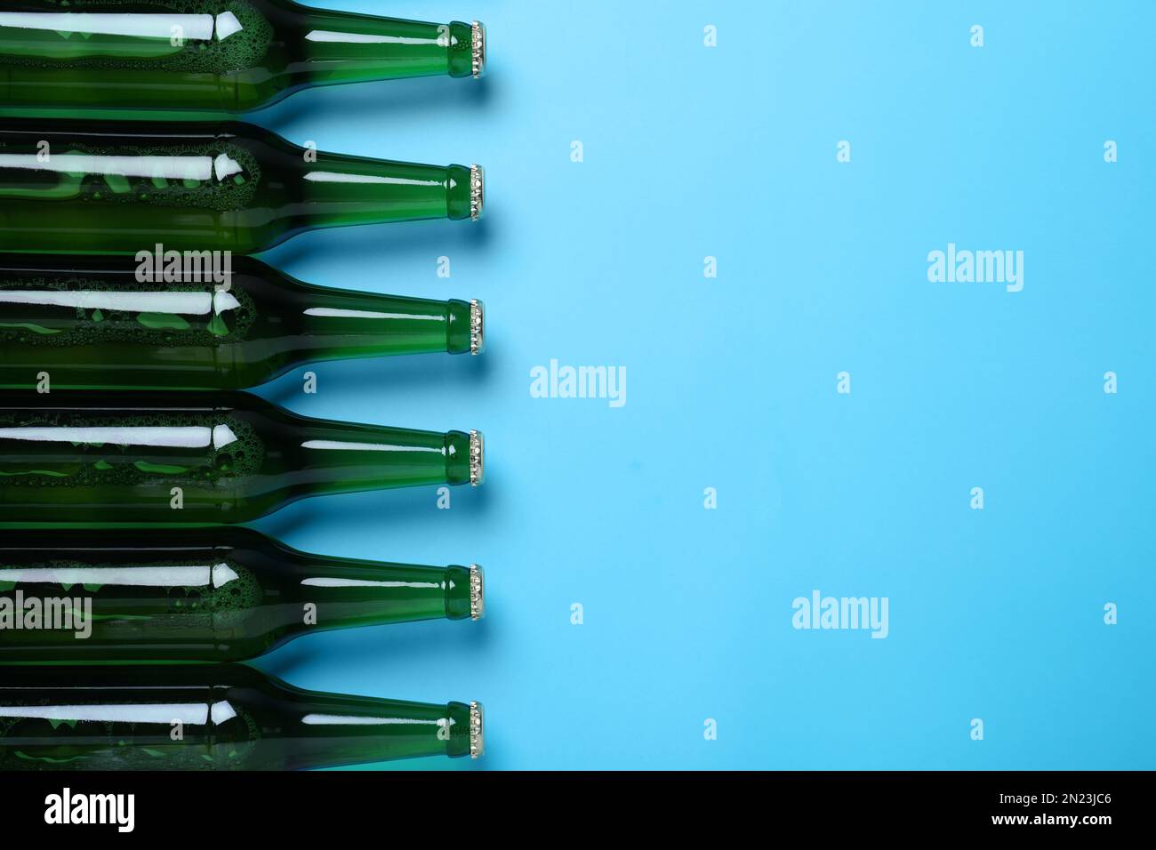 Bottles of beer on light blue background, flat lay. Space for text ...