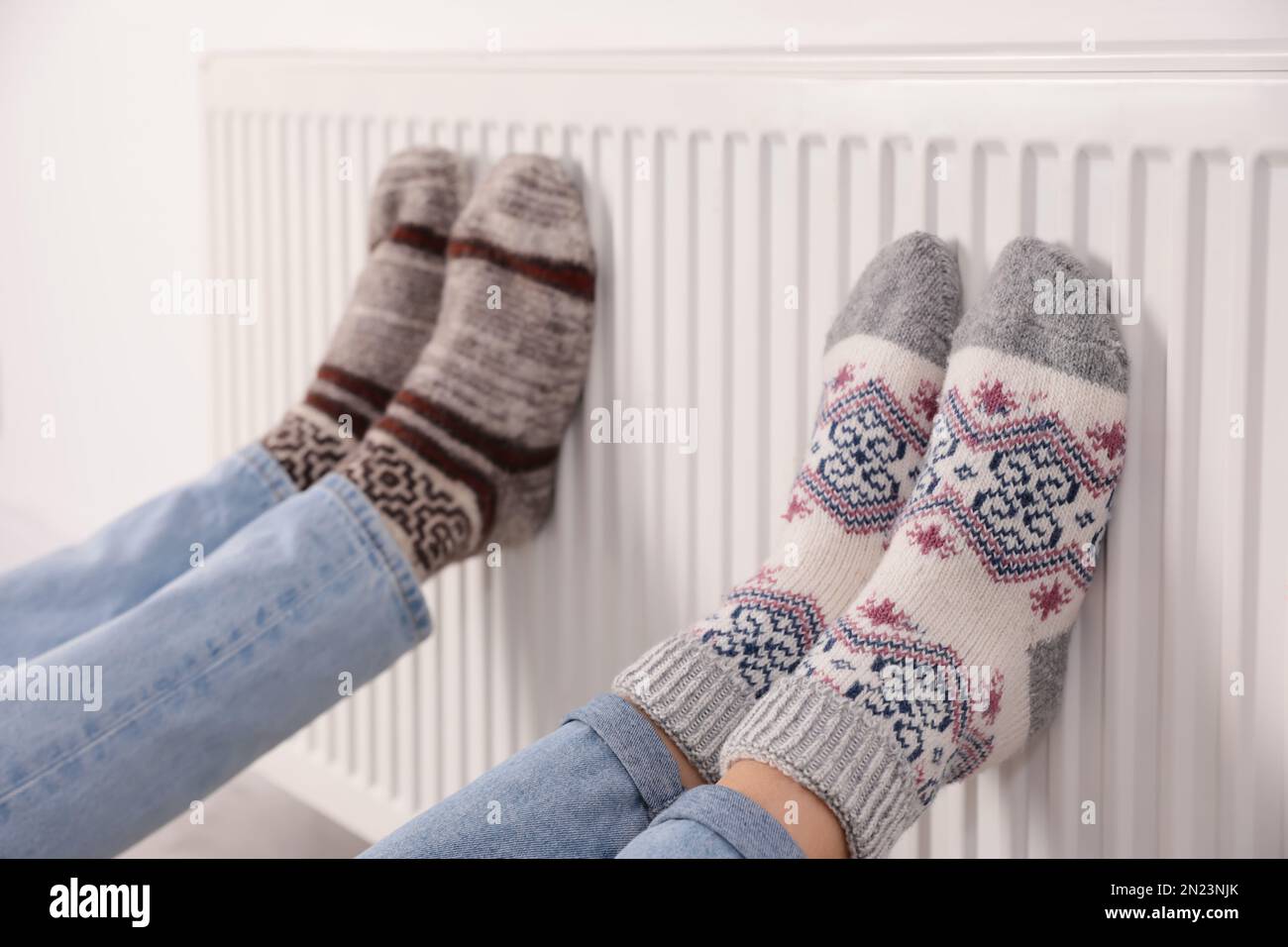 Couple warming legs on heating radiator indoors, closeup Stock Photo ...