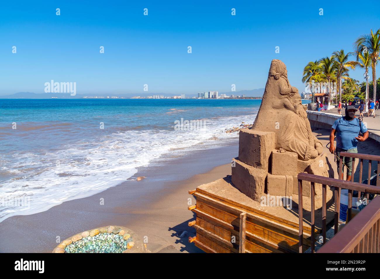 An artist sprays water on a sand statue along Olas Altas Playa del ...