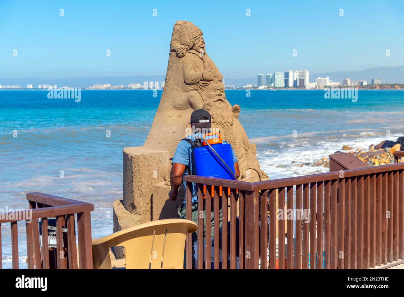 An artist sprays water on a sand statue along Olas Altas Playa del ...