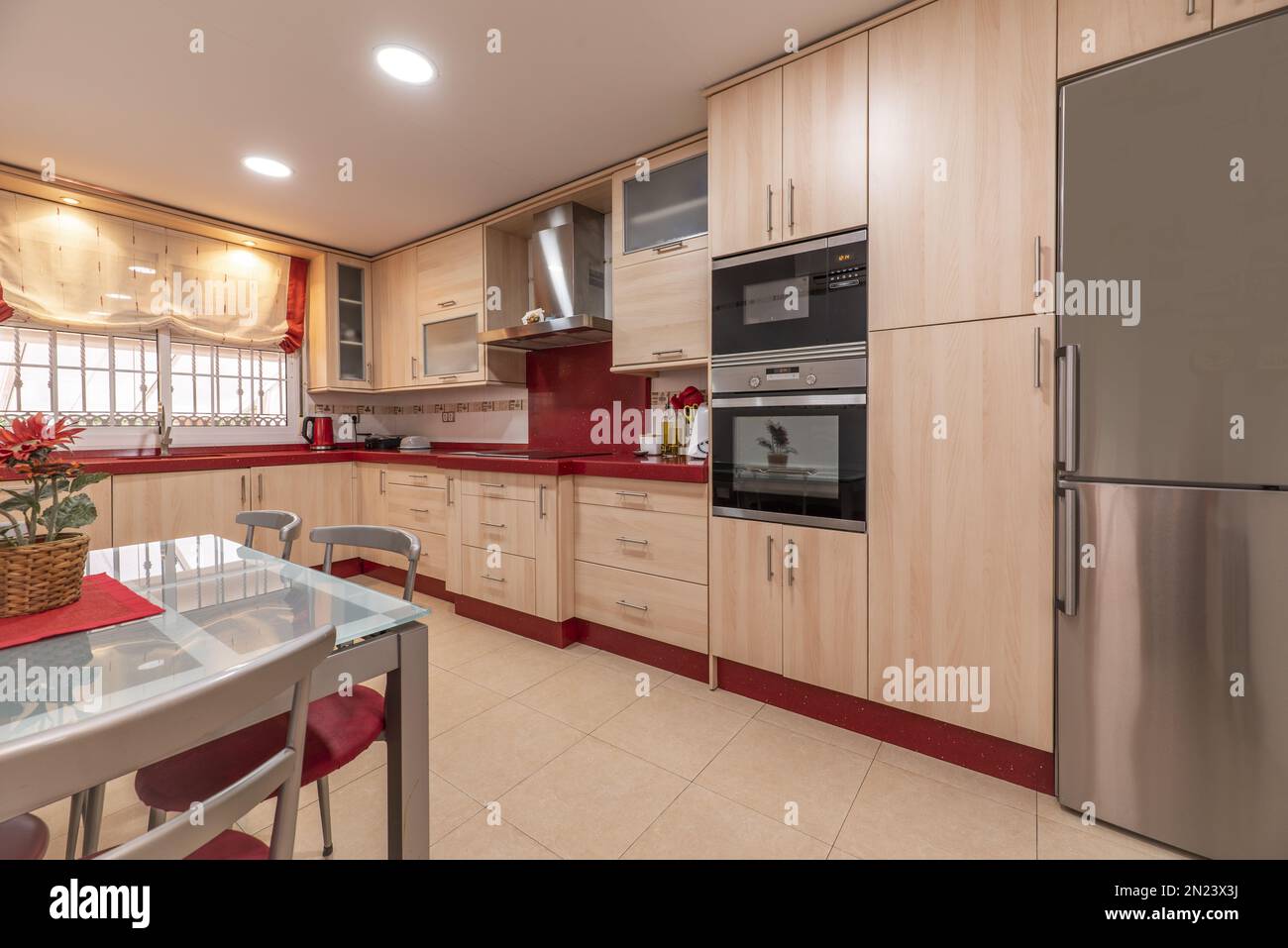 Kitchen with metal-knob cabinets in light wood cabinets, red ...