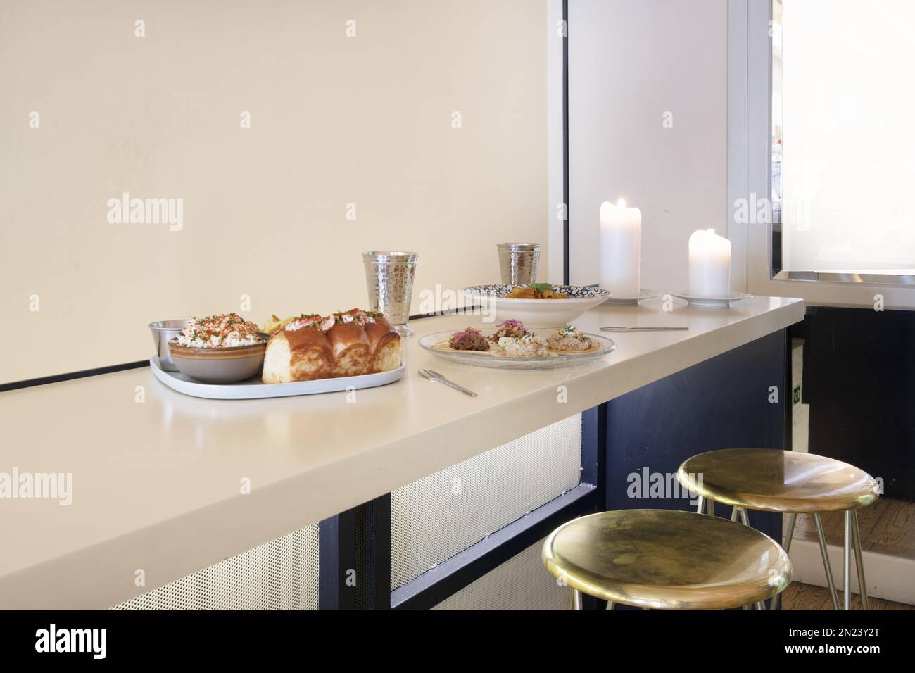 High table of a restaurant with plates of food and stools with golden ...