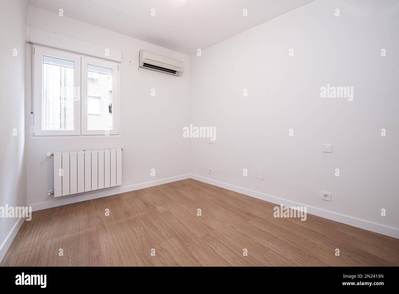 Empty room with white aluminum radiator under the window and laminate ...