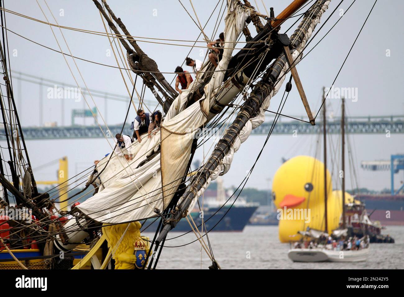 Crew members work on the L’Hermione as a giant rubber duck sails up the ...