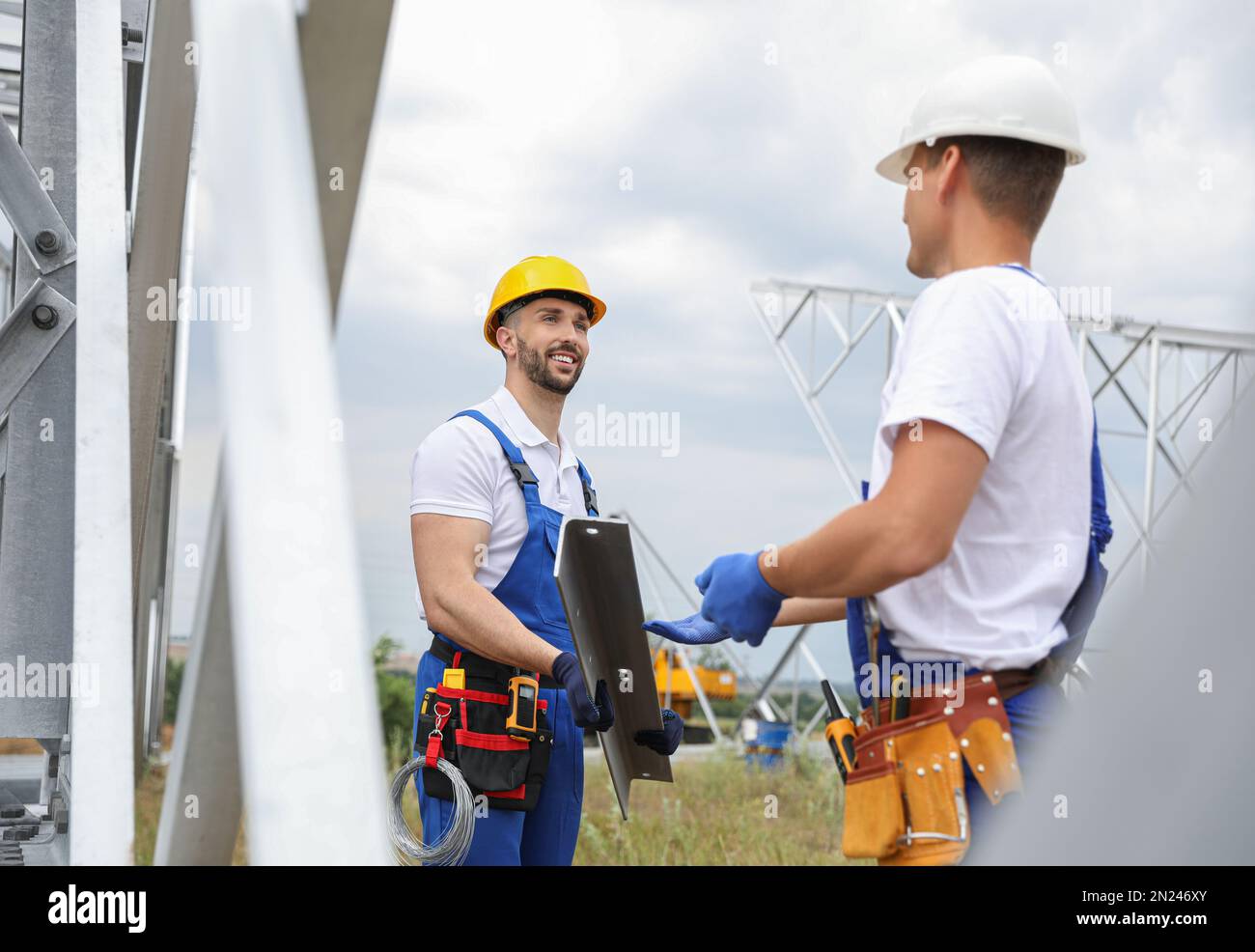 Workers building high voltage tower construction outdoors. Installation ...