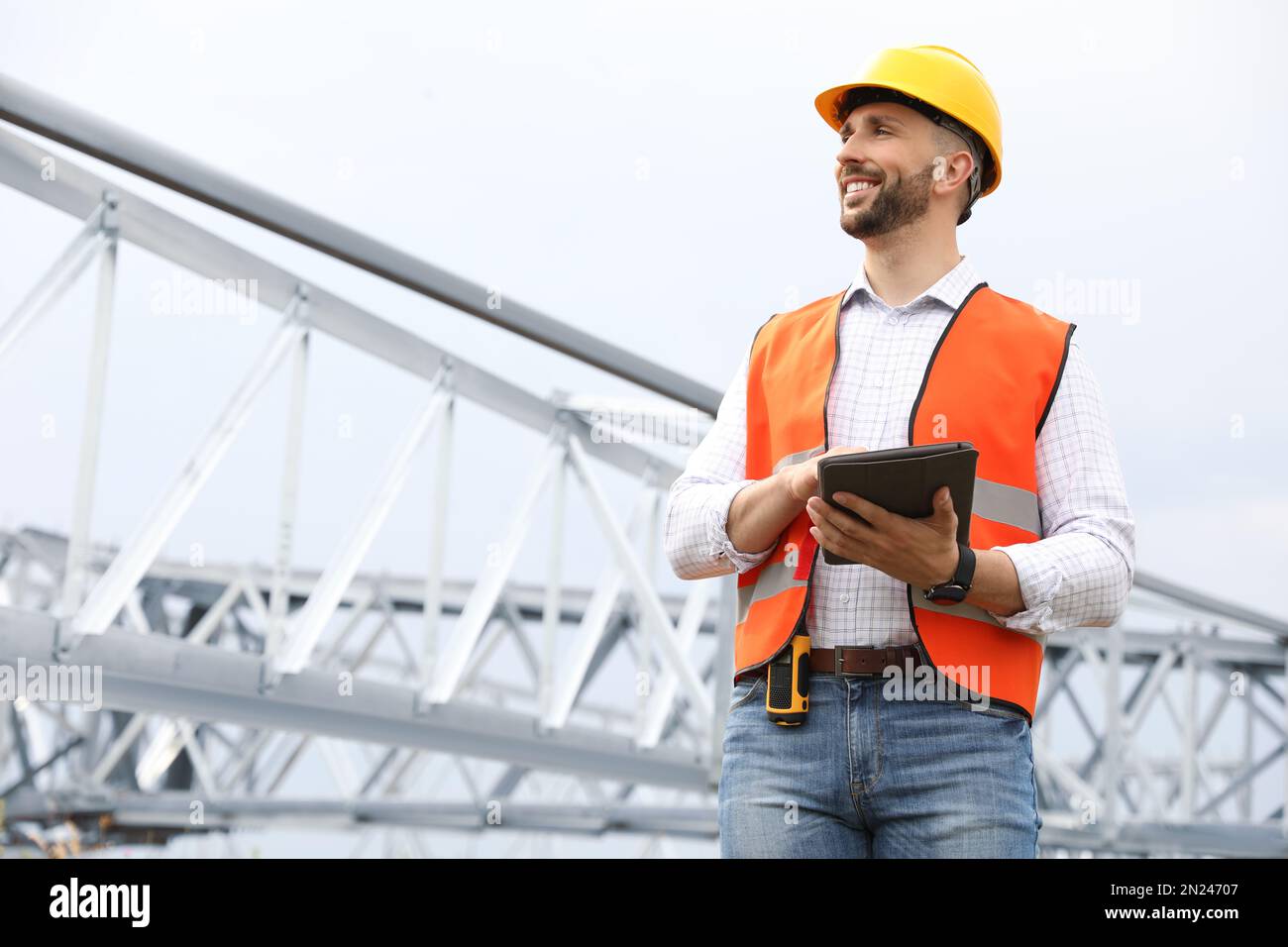 Professional engineer with tablet near high voltage tower construction ...