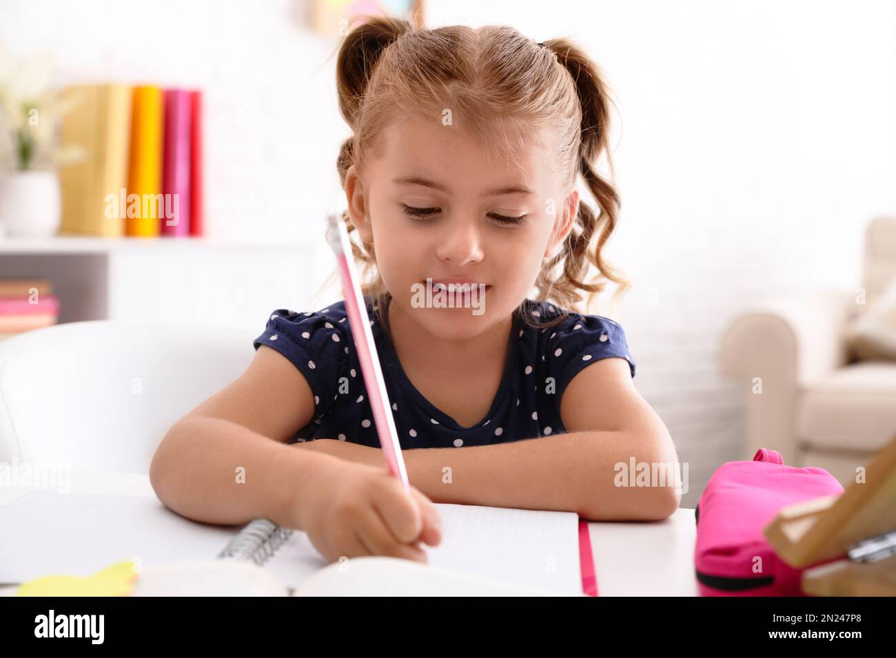 Cute little girl doing homework at table Stock Photo - Alamy