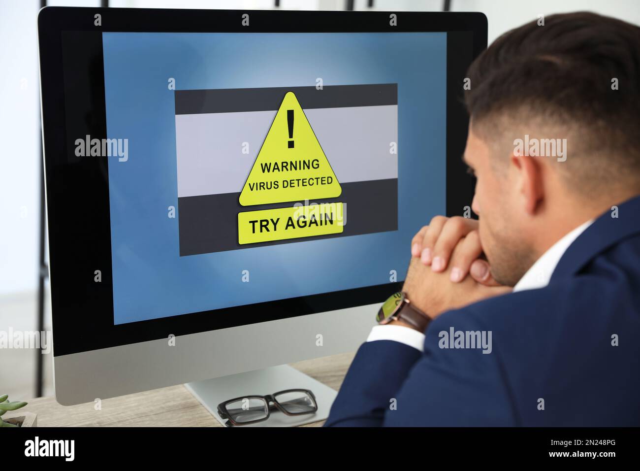 Office worker in front of computer with warning about virus attack on ...