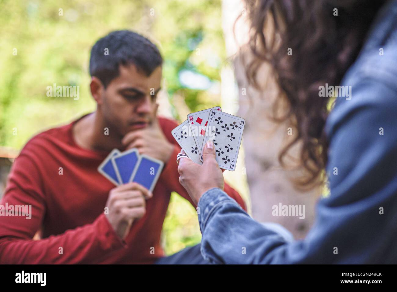 Card playing in a spring garden: Couple are sitting on a table ...