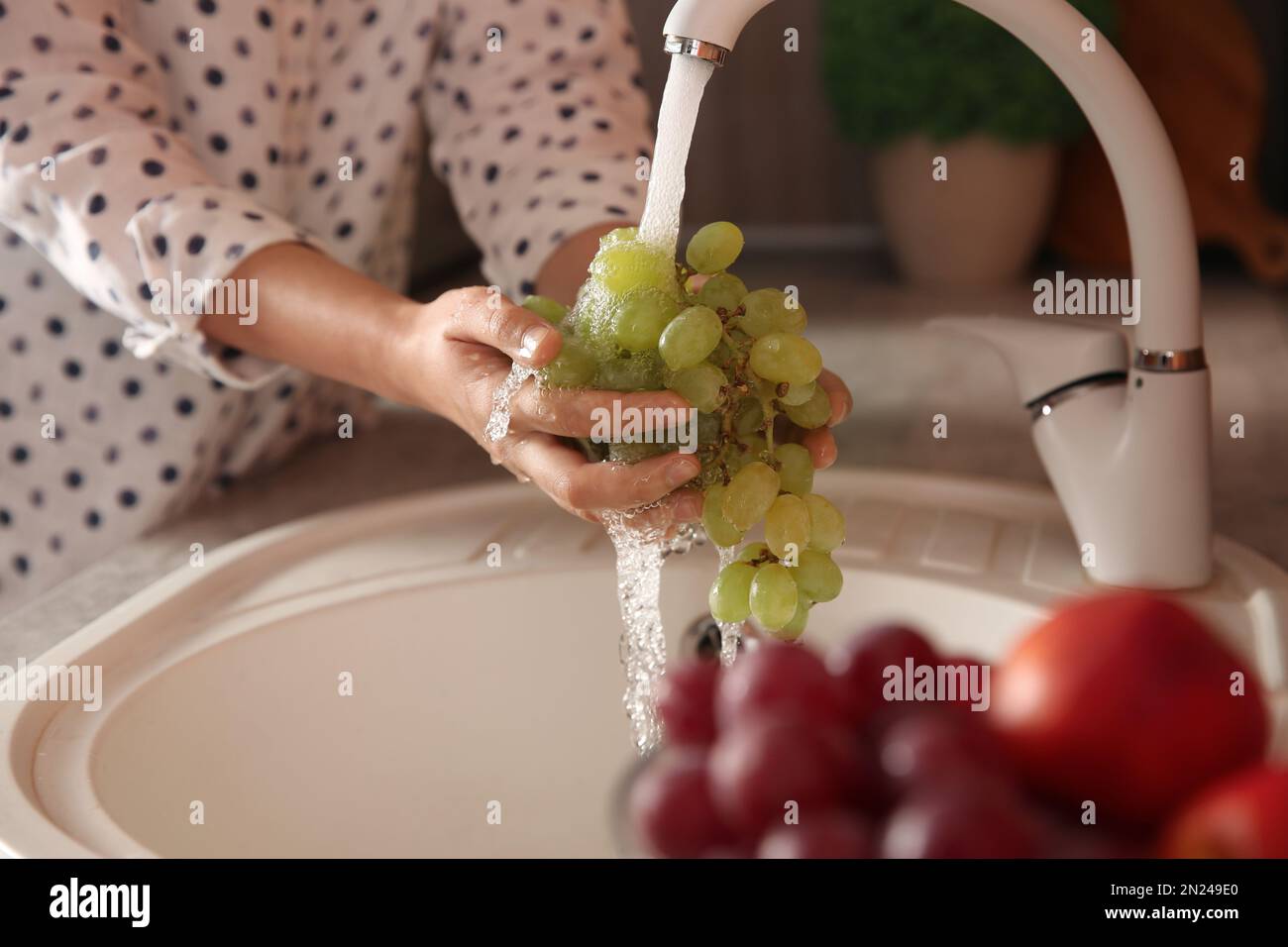 Woman washing fresh grapes in kitchen sink, closeup Stock Photo - Alamy