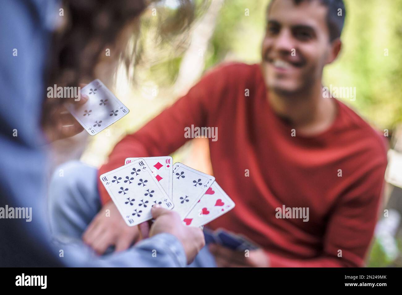 Card playing in a spring garden: Couple are sitting on a table ...
