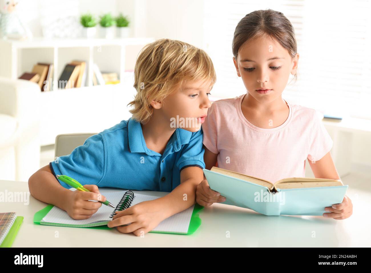 Little boy and girl doing homework at table indoors Stock Photo - Alamy