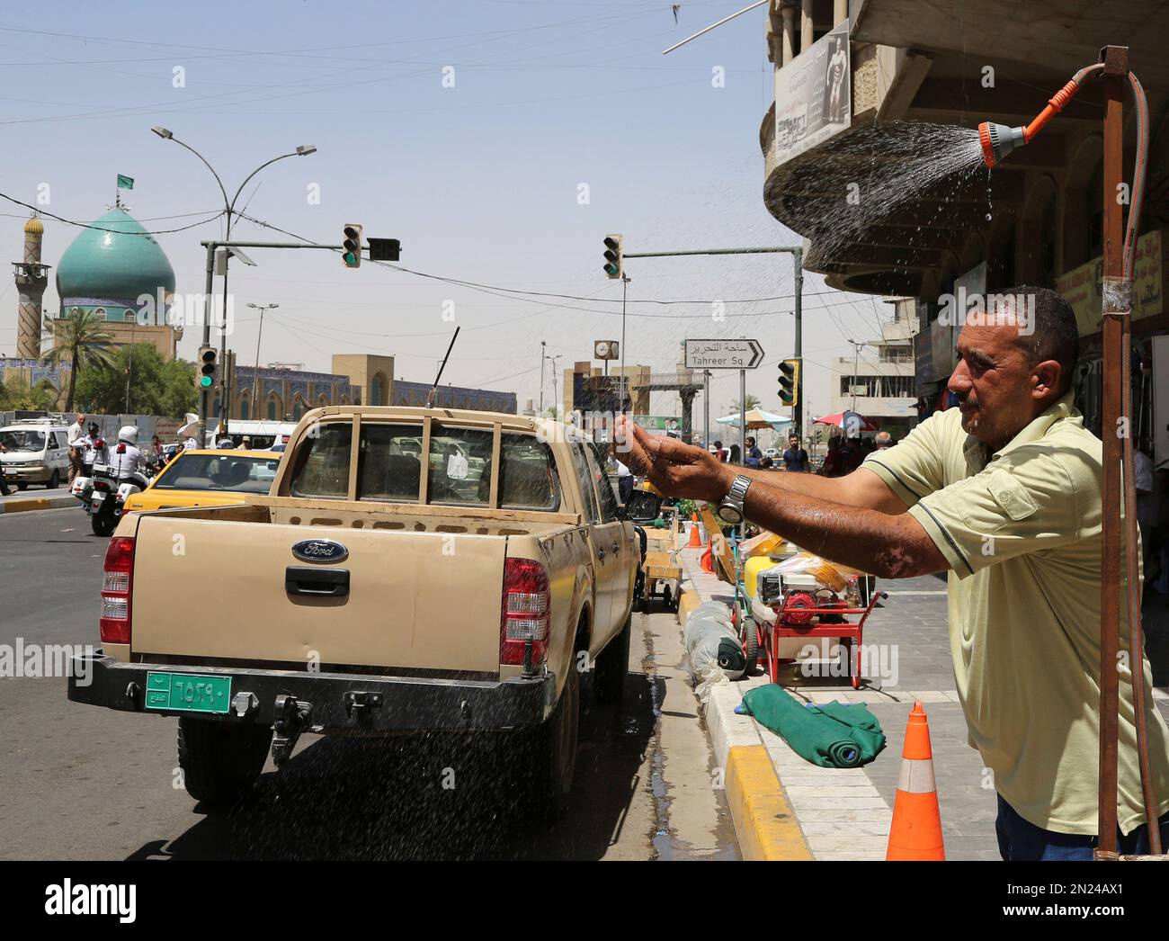 An Iraqi man takes advantage of a public shower to cope with the summer ...