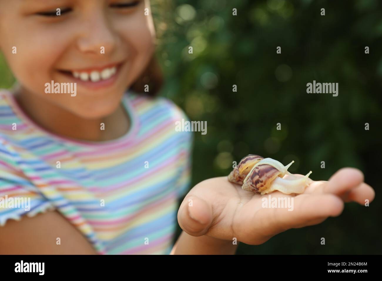 Girl playing with cute snails outdoors, focus on hand. Child spending ...