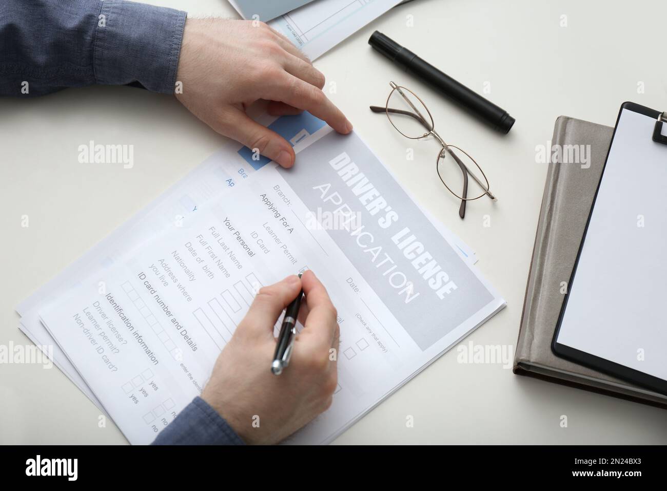 Man filling in driver's license application form at white table, top view Stock Photo - Alamy