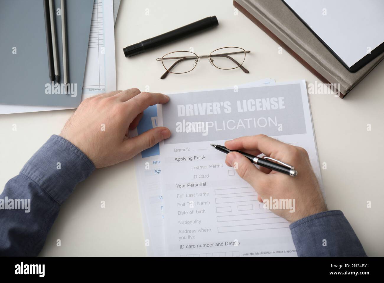 Man filling in driver's license application form at white table, top ...