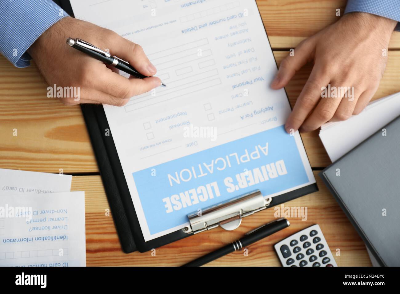 Man filling in driver's license application form at wooden table, top view Stock Photo - Alamy