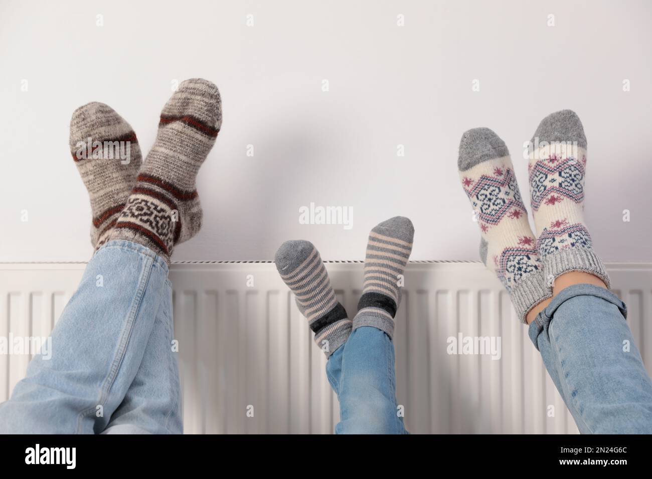 Family warming legs on heating radiator near white wall, closeup Stock ...
