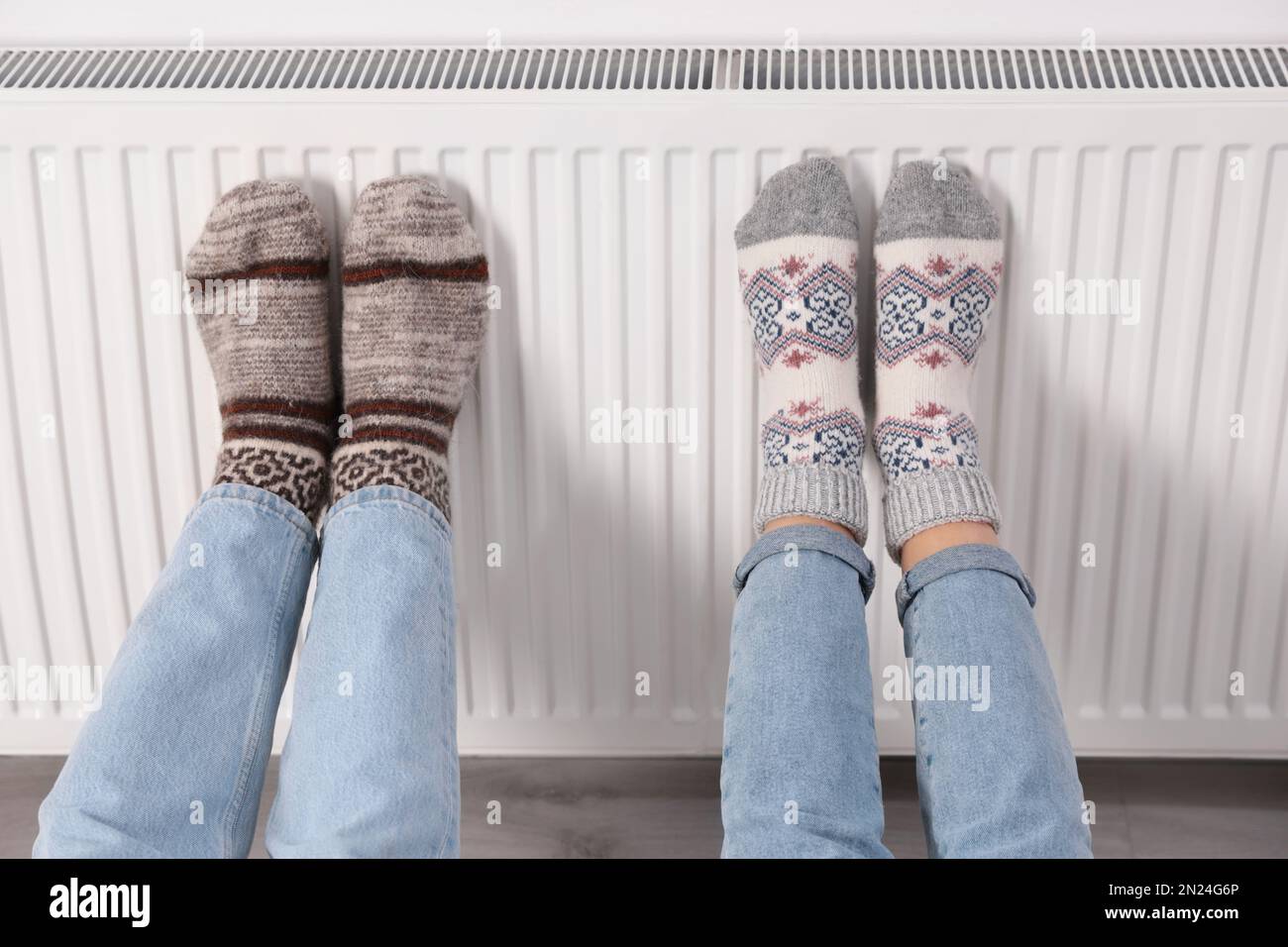 Couple warming legs on heating radiator indoors, closeup Stock Photo ...