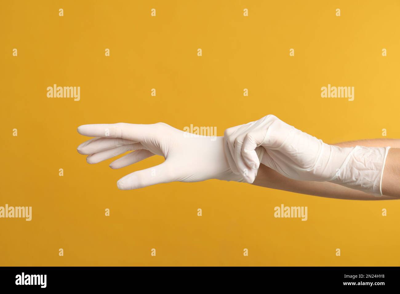 Doctor wearing medical gloves on yellow background, closeup Stock Photo ...