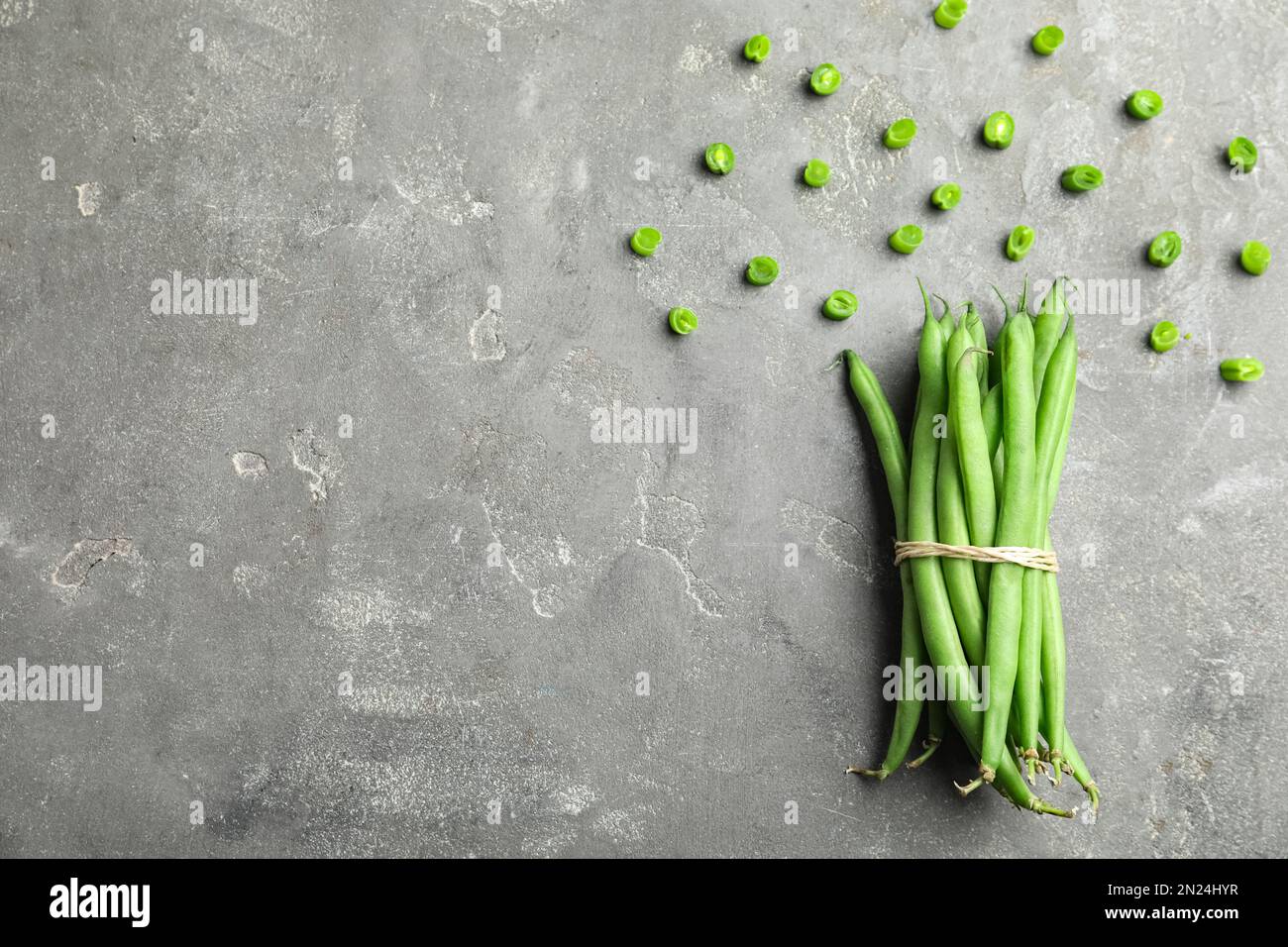 Flat lay composition with fresh green beans on grey table. Space for ...