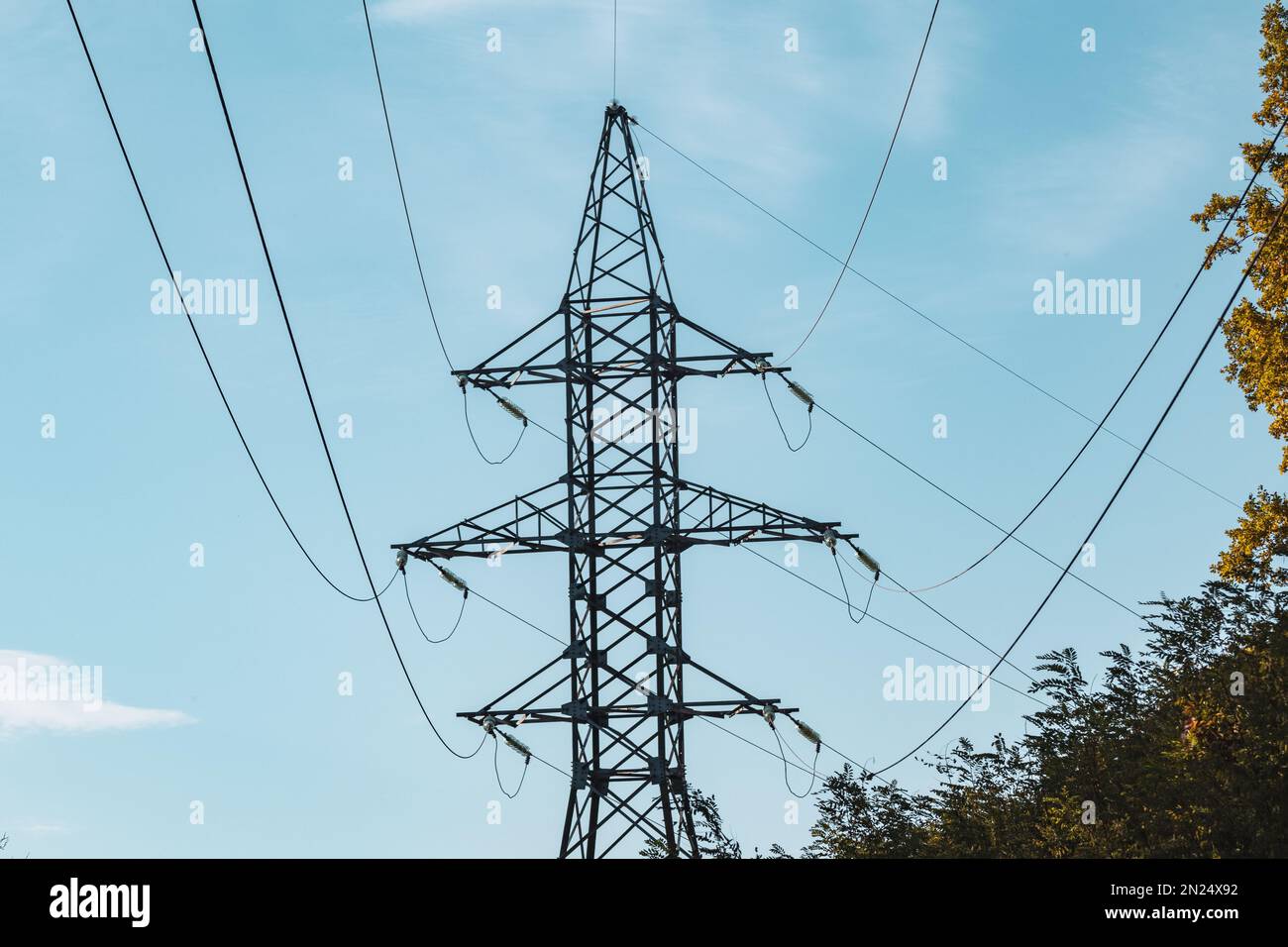 High voltage electric transmission line pylon tower with wires on blue ...