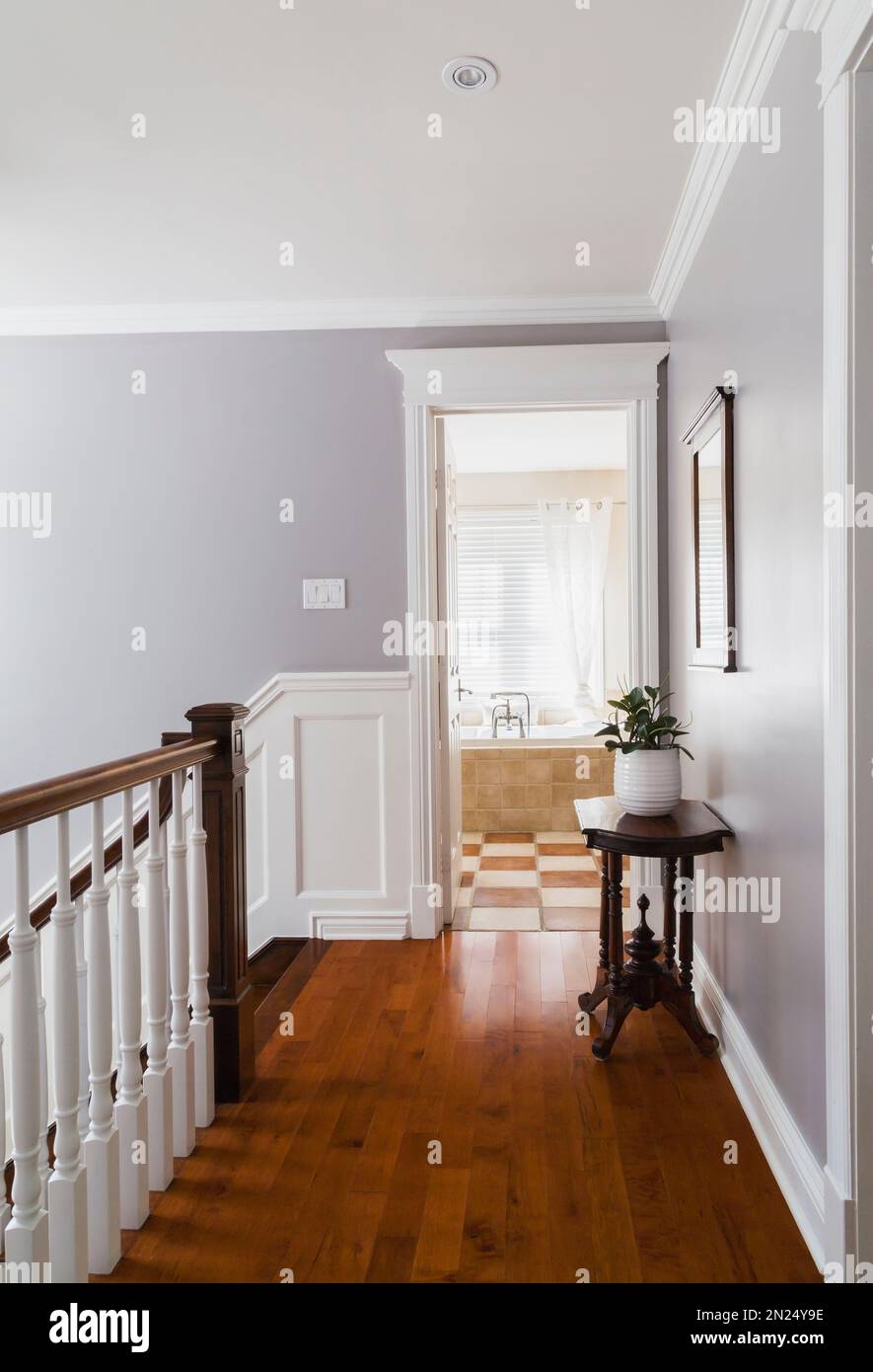 Brown wooden handrail with white spindles and hallway with cherry wood ...