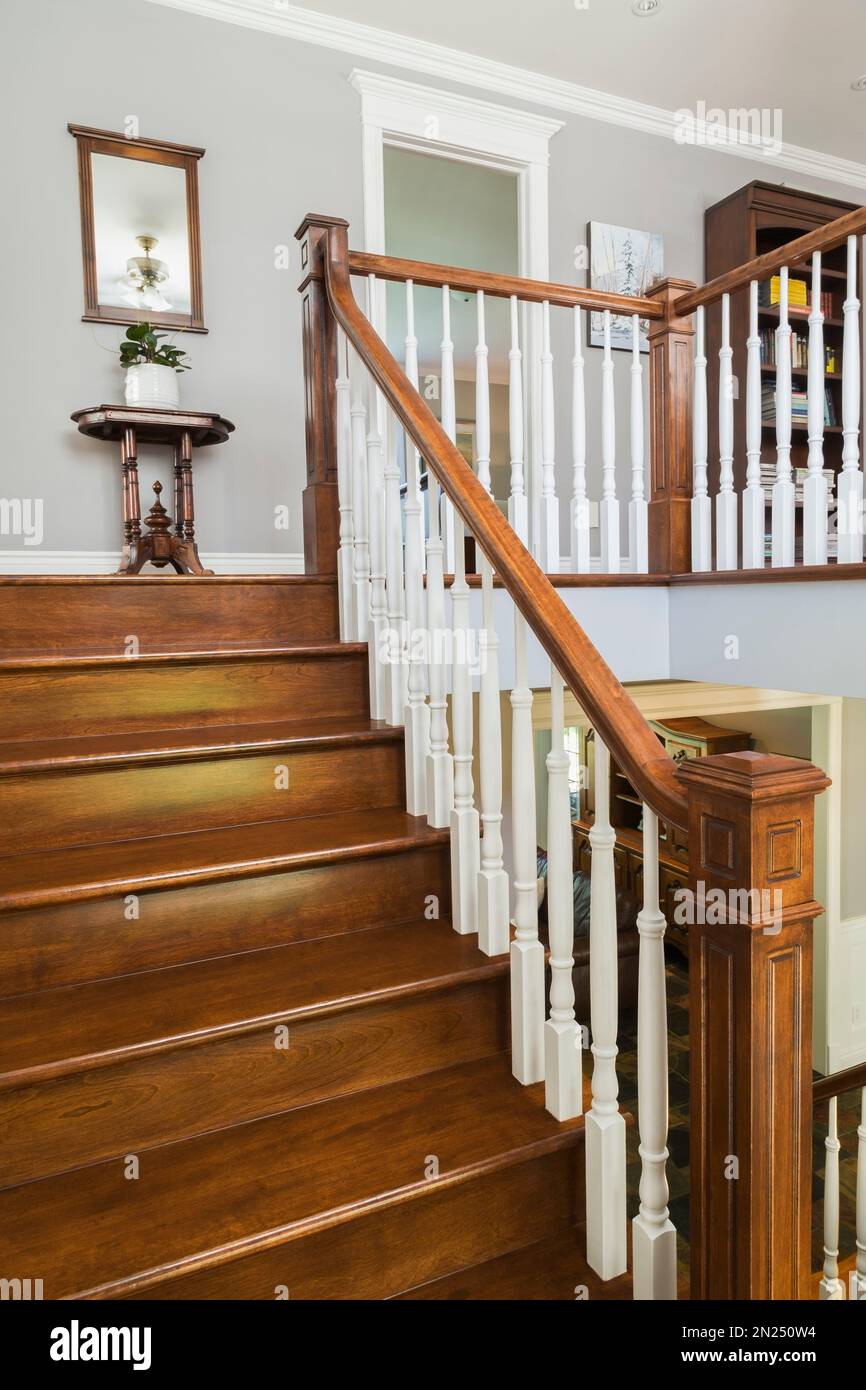 Cherry wood stairs and handrail with white spindles leading to upper ...