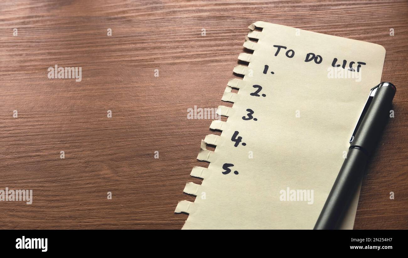 A list of to do list written on a piece of paper with pen on wooden ...