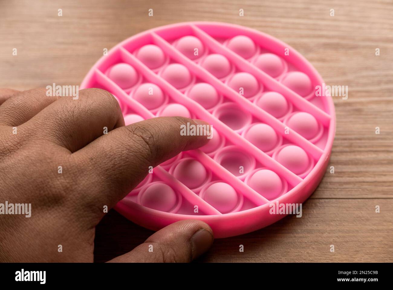 Selective focus of hand pushing anti stress sensory toy fidget push pop ...